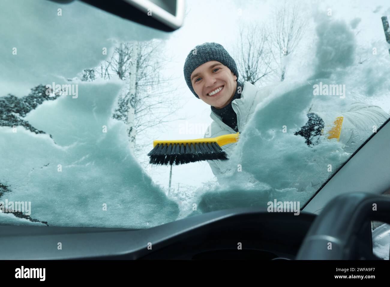 Man cleaning snow from car windshield, view from inside Stock Photo - Alamy