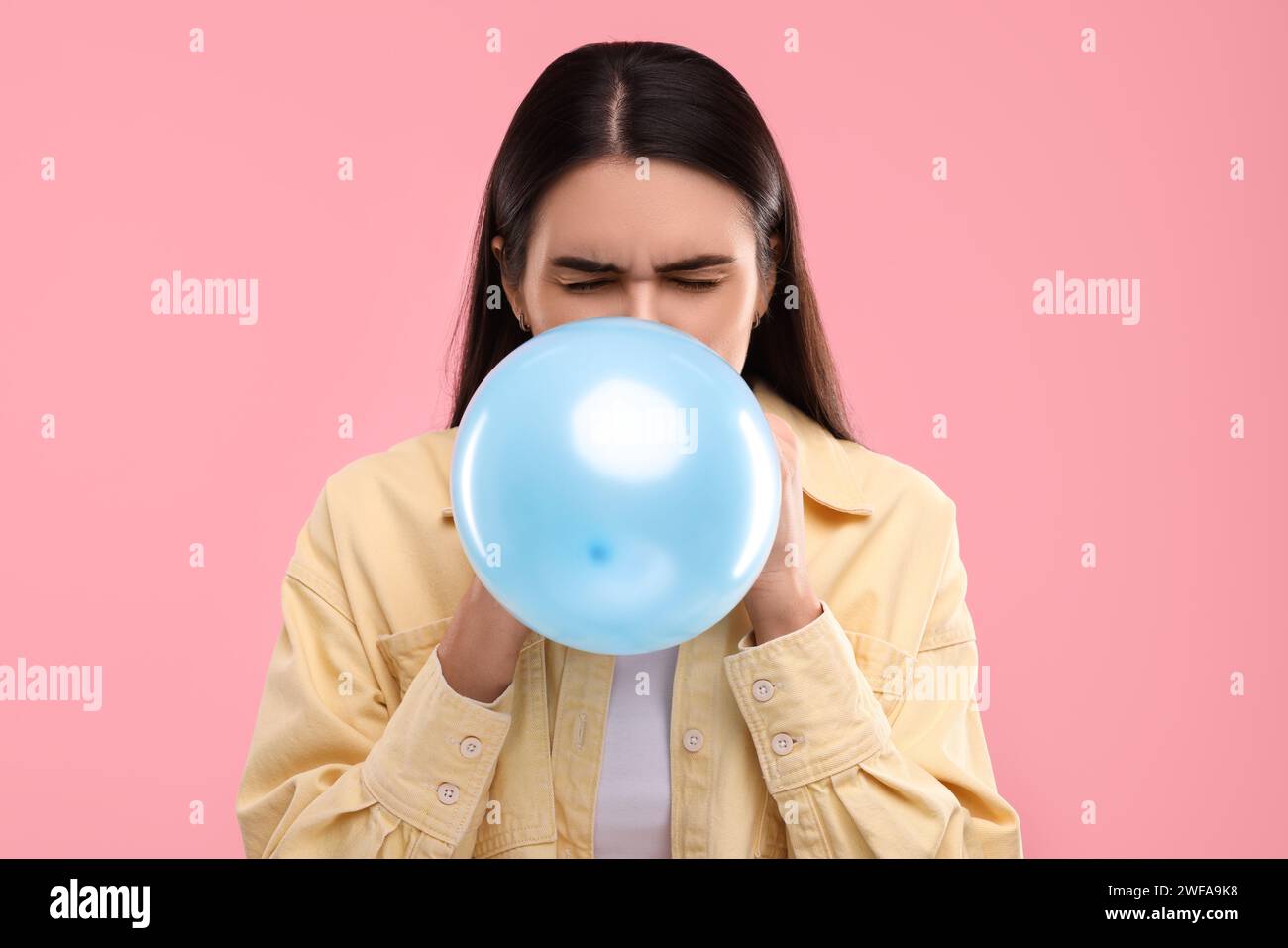 Woman inflating light blue balloon on pink background Stock Photo - Alamy