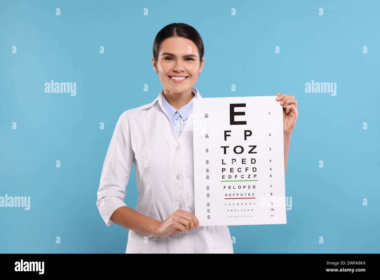 Ophthalmologist with vision test chart on light blue background Stock ...