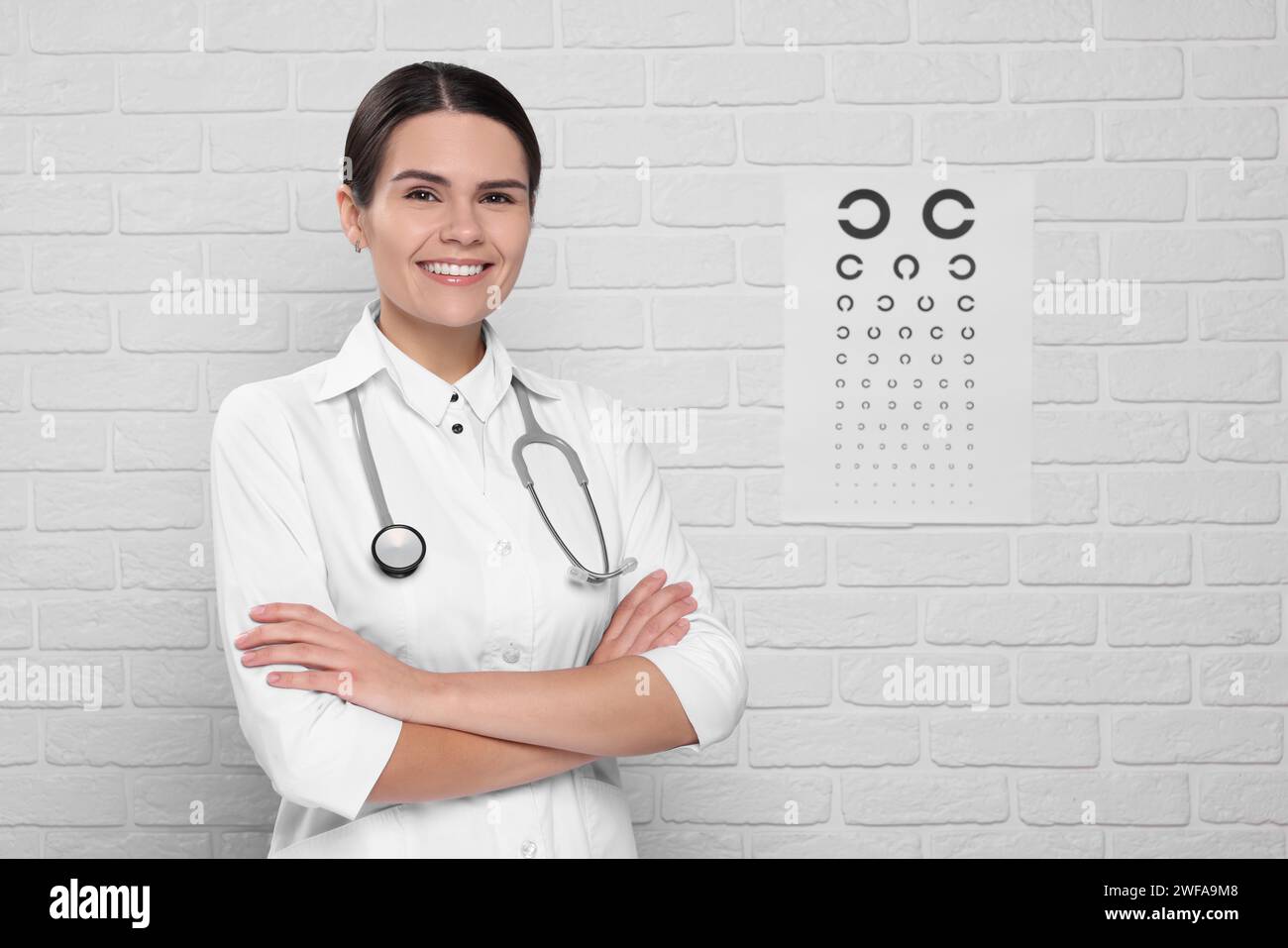 Ophthalmologist near vision test chart on white brick wall Stock Photo ...