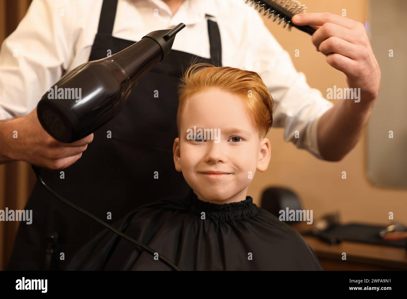 Professional hairdresser drying boy's hair in beauty salon, closeup ...