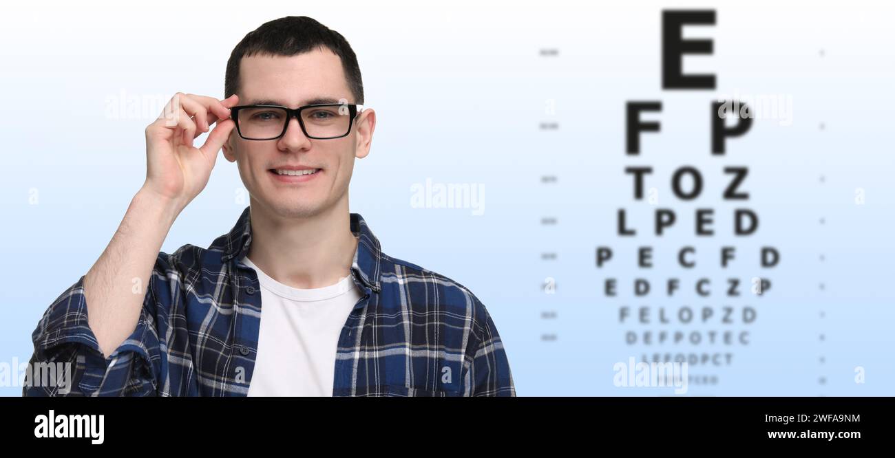 Vision test. Young man in glasses and eye chart on gradient background ...