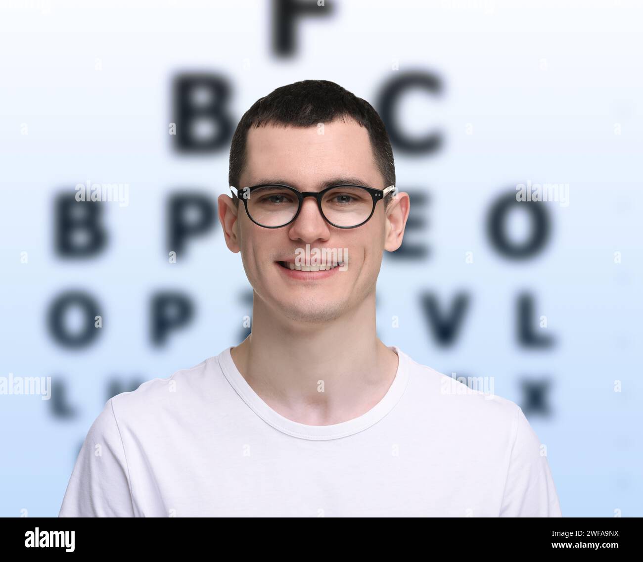 Vision test. Young man in glasses and eye chart on gradient background ...