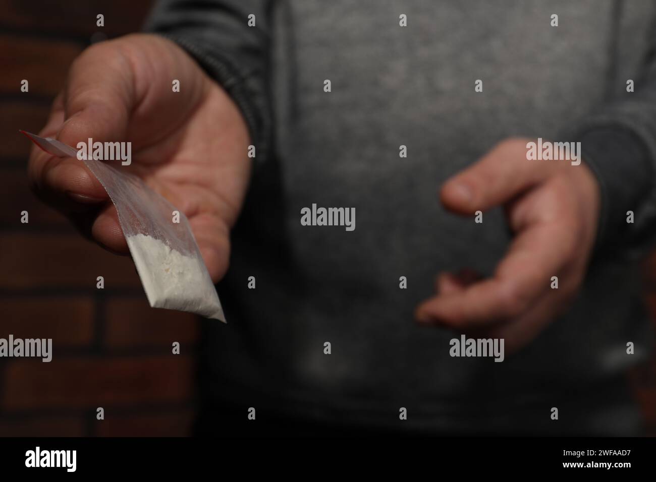 Drug addiction. Man with plastic bag of cocaine on blurred background ...