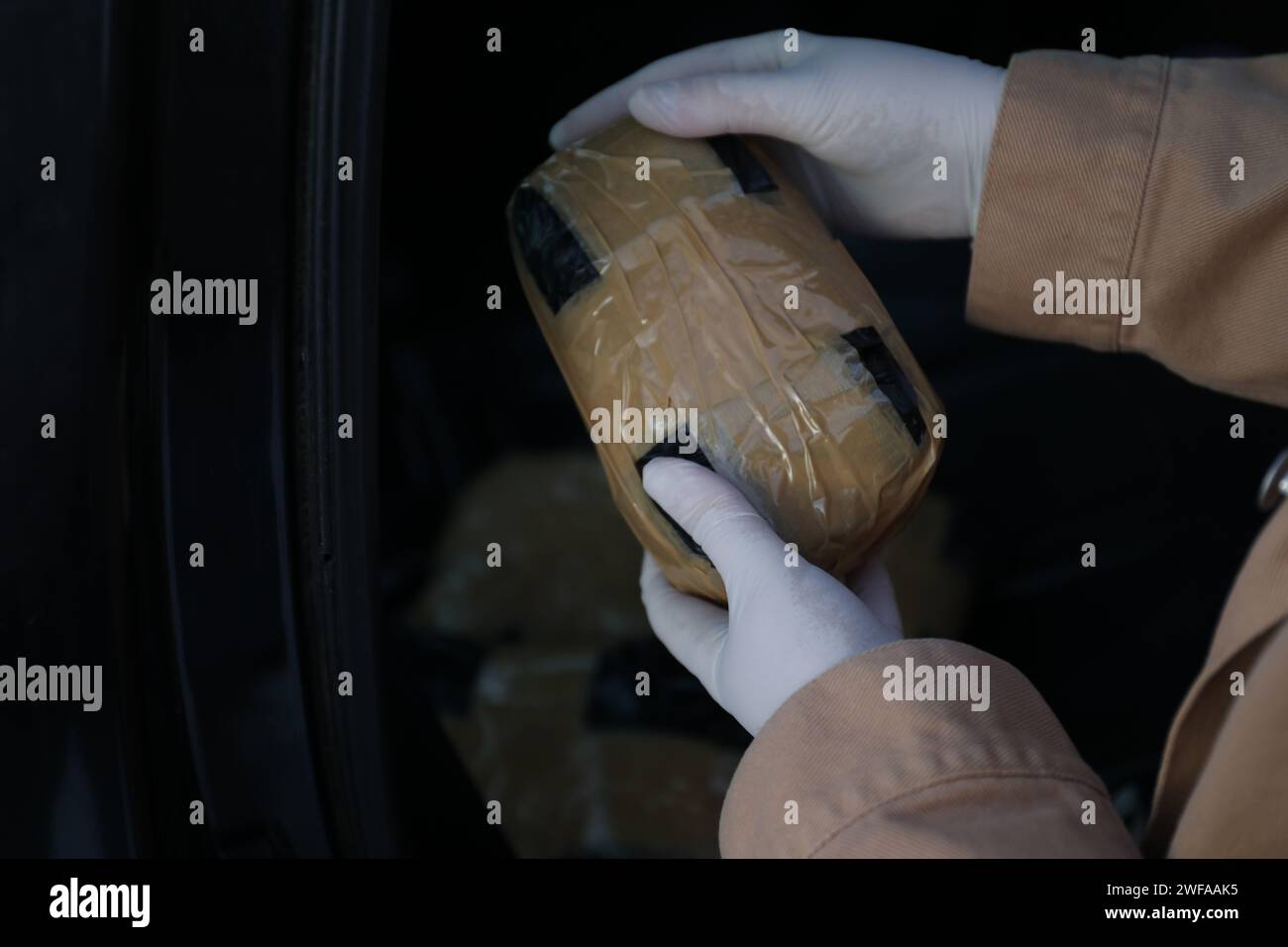 Man with package of narcotics on dark background, closeup. Space for ...