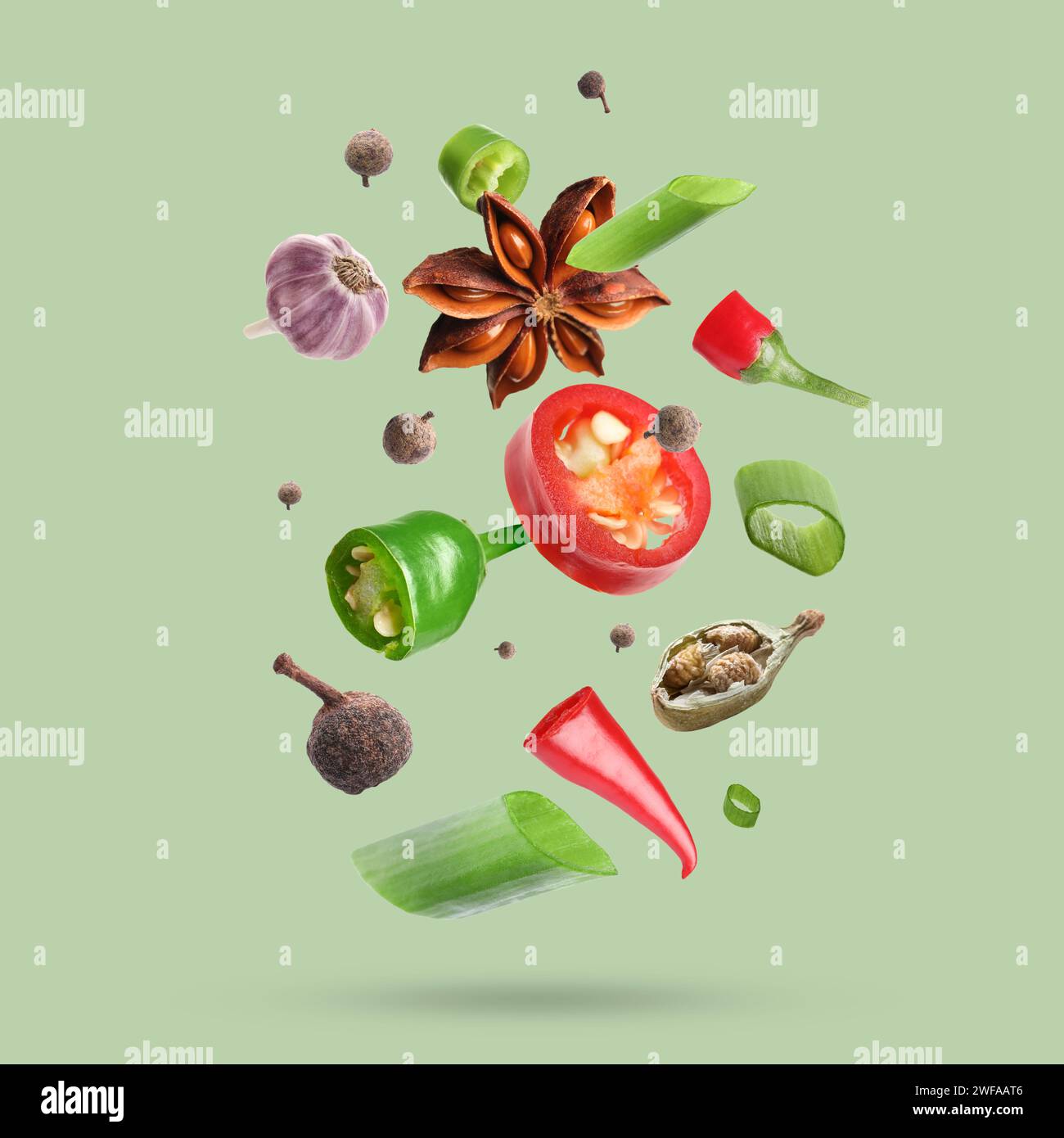 Different spices falling on light green background Stock Photo - Alamy