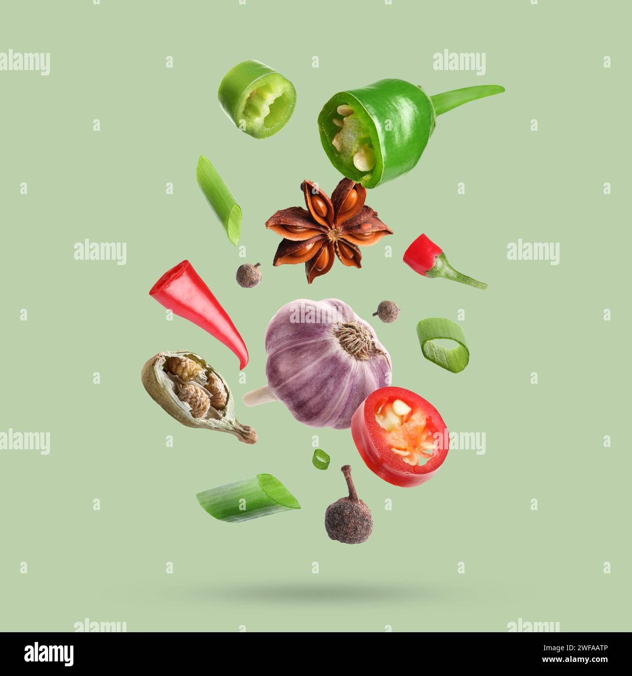 Different spices falling on light green background Stock Photo - Alamy
