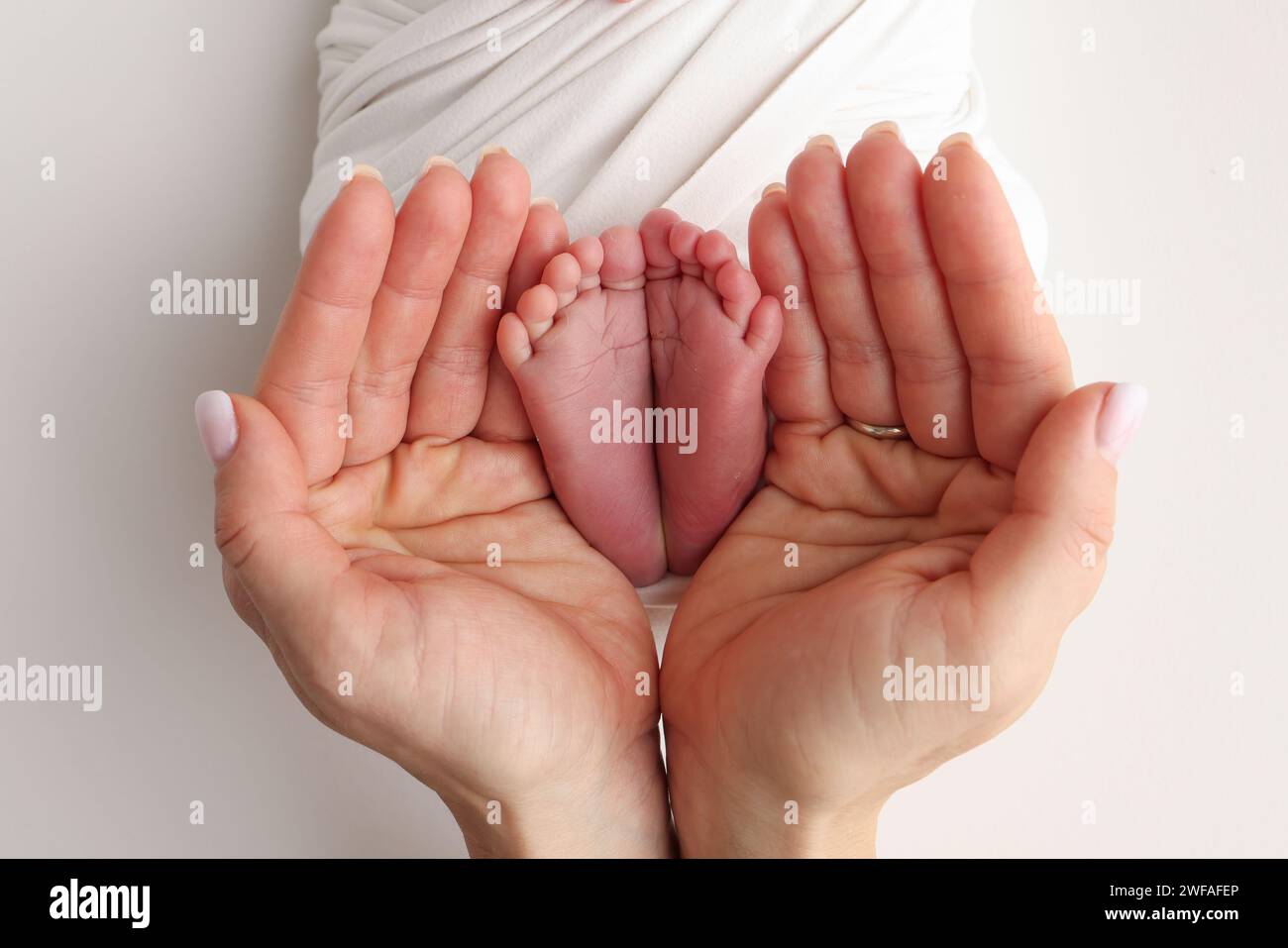 The palms of the father, the mother are holding the foot of the newborn ...