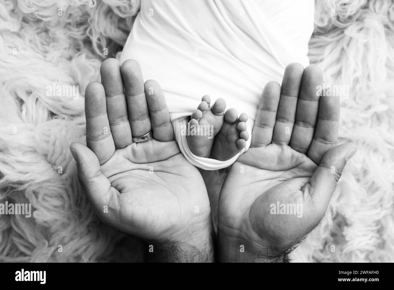 The palms of the father, the mother are holding the foot of the newborn ...