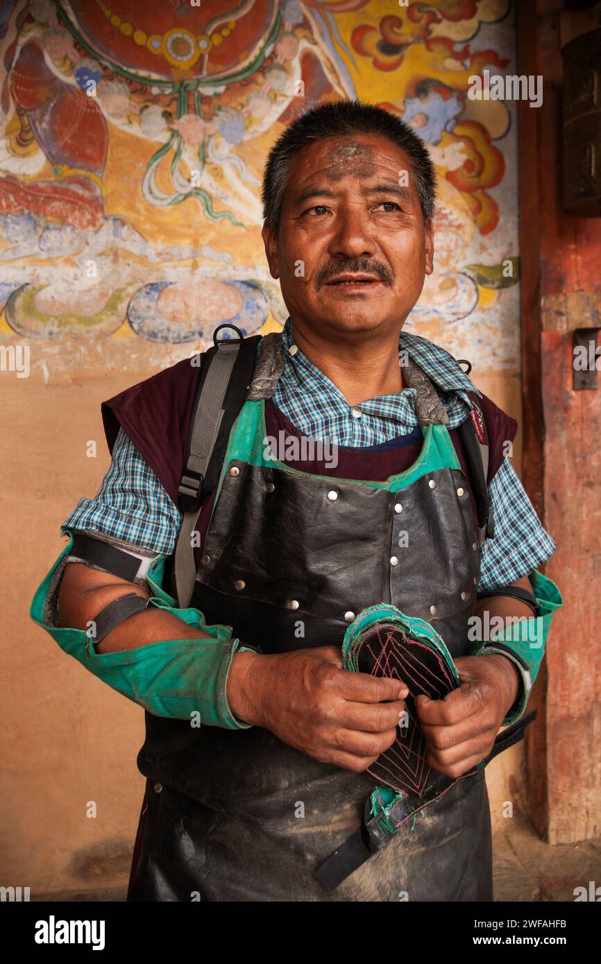 A Bhutanese man holds fabric knee protectors he used while completing ...