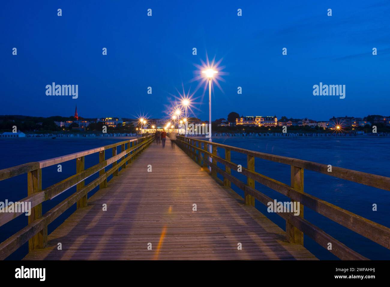 Nocturnal pier with illuminated street lamps and star effect ...