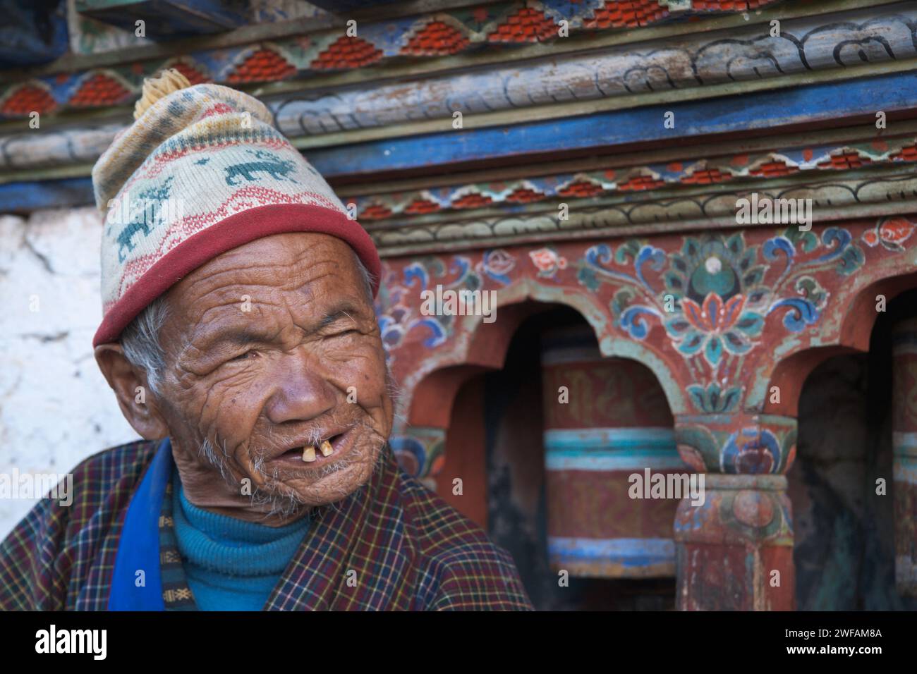 An animated old man stands in front of prayer wheels at an ancient ...