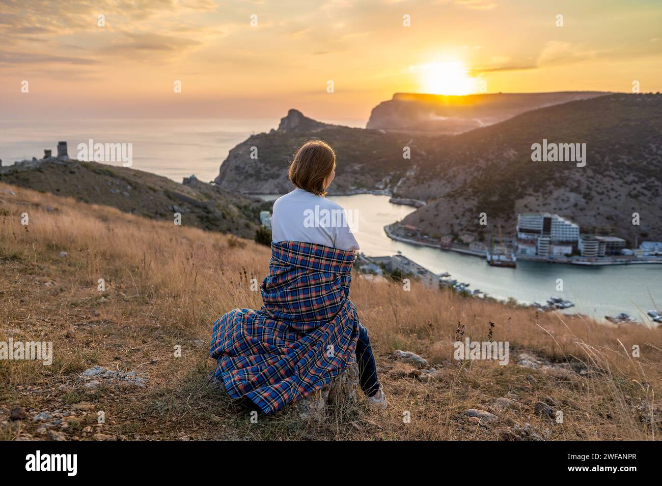 Happy woman on sunset in mountains. Woman siting with her back on the ...