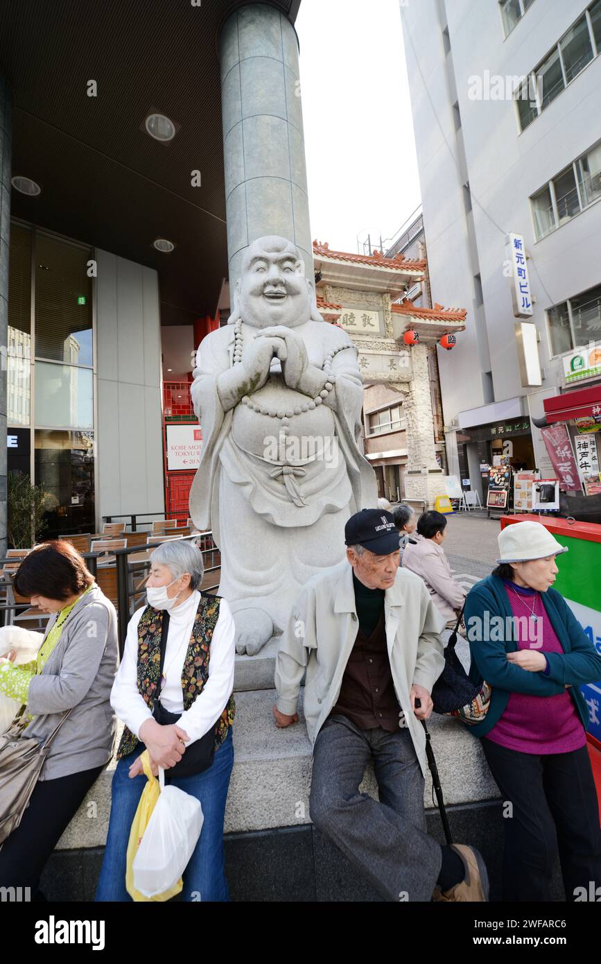 Elderly Japanese people sitting by a laughing Buddha statue at the ...