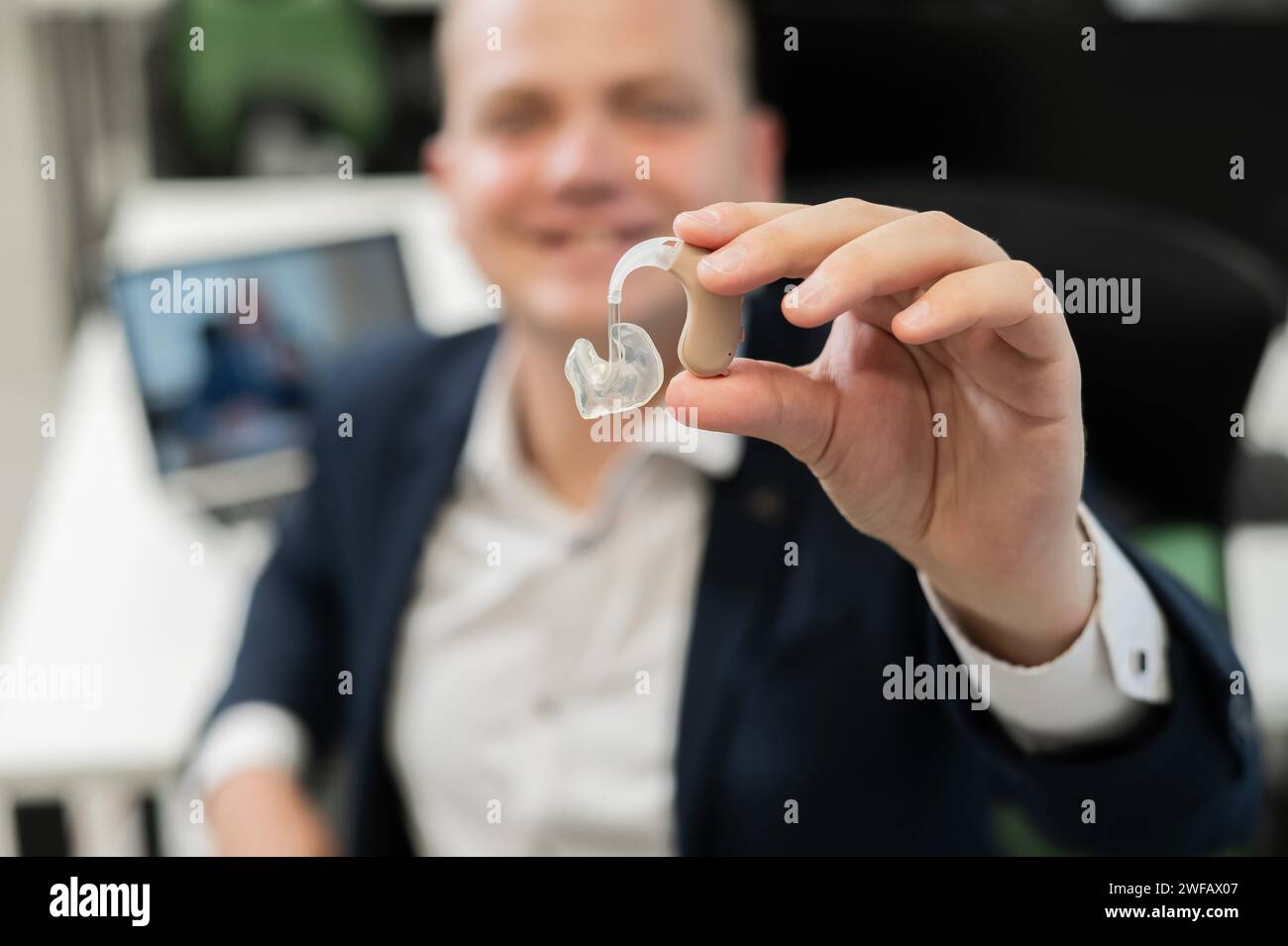 Deaf man working holds hearing aid while sitting in office Stock Photo ...