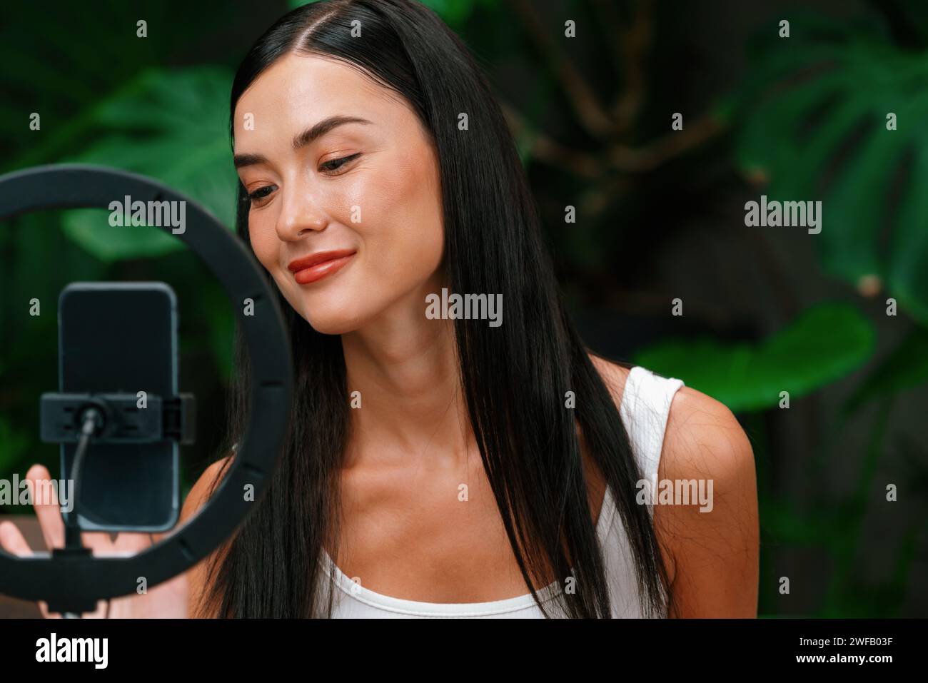 Young woman making natural beauty and cosmetic tutorial on green plant ...