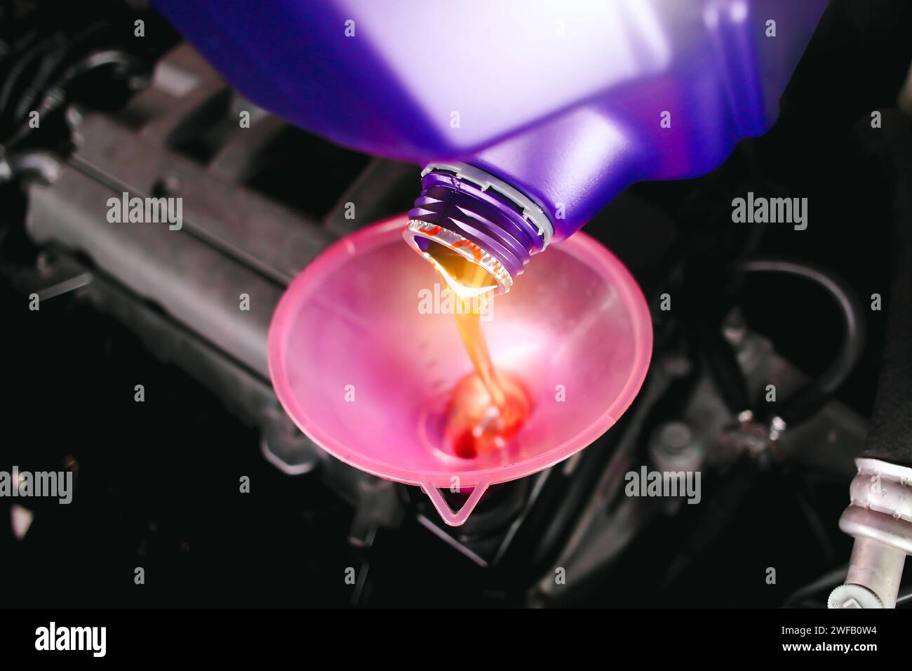 Engine oil poured into a funnel in the engine oil filler of the car ...