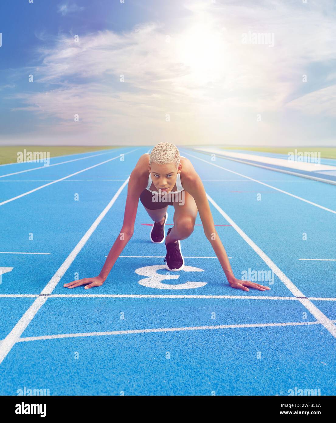 An African American female athlete stands poised at the starting line ...
