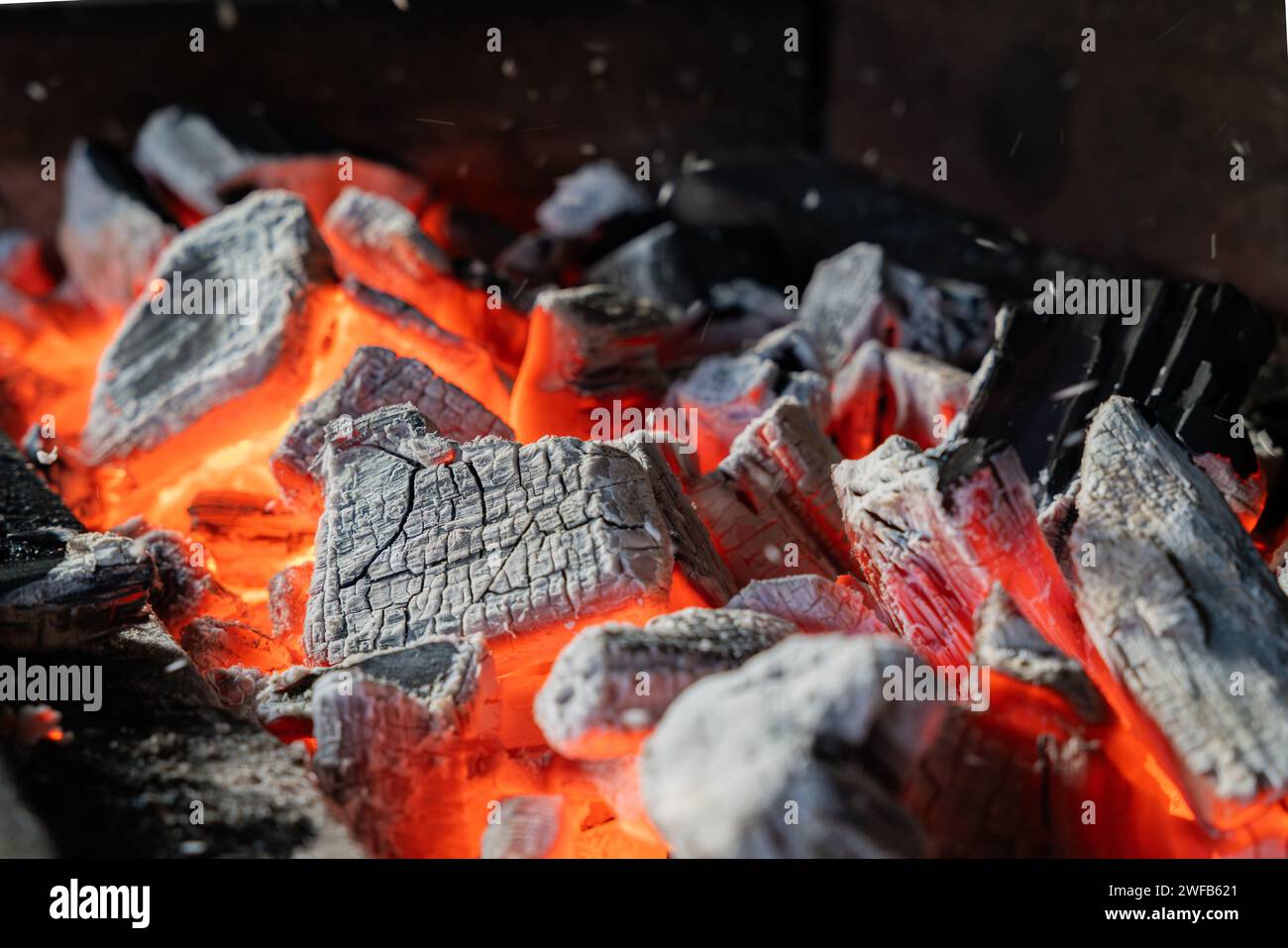 Photo of hot sparking live-coals burning in a barbecue background. A ...