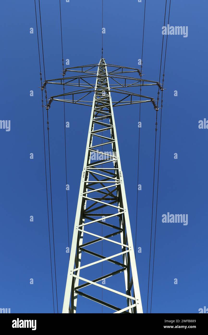 High voltage pylon standing against blue sky, industrial construction ...