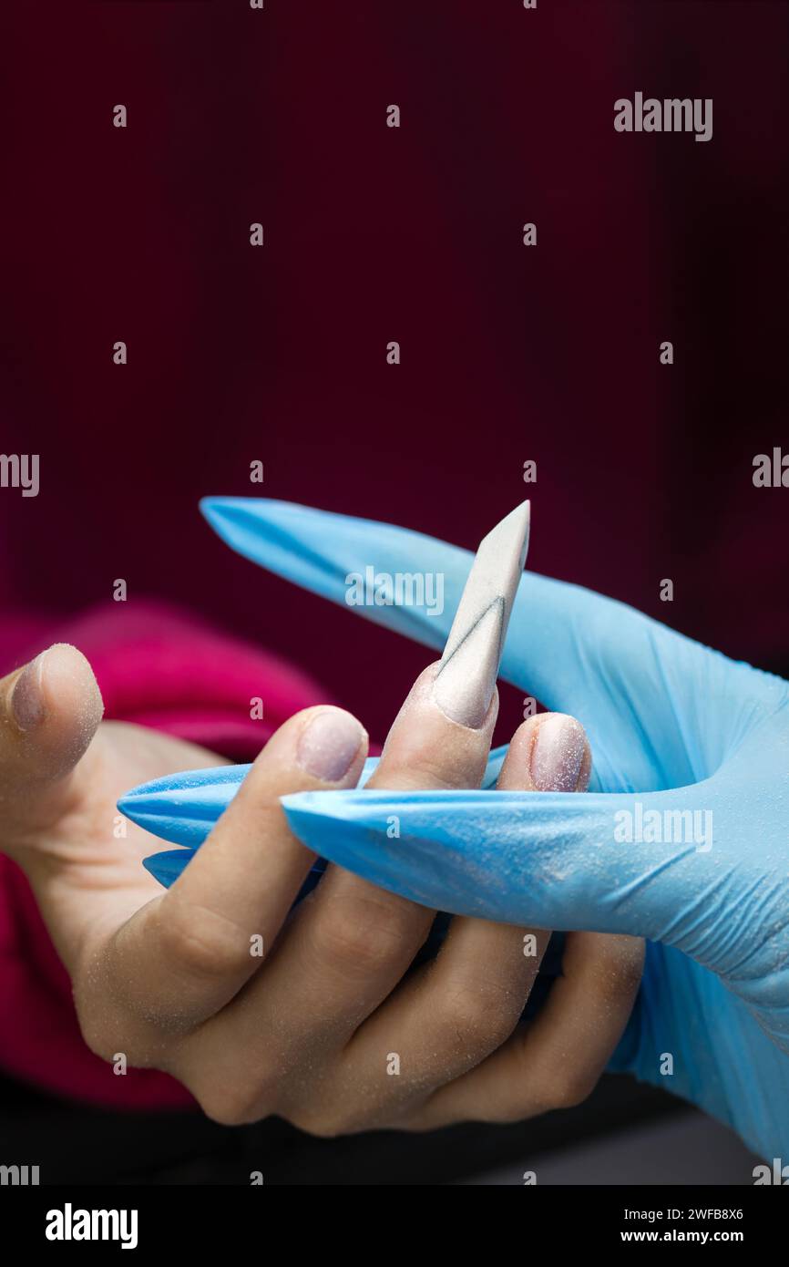 Close-up of edge nail filing and shaping during a manicure session ...