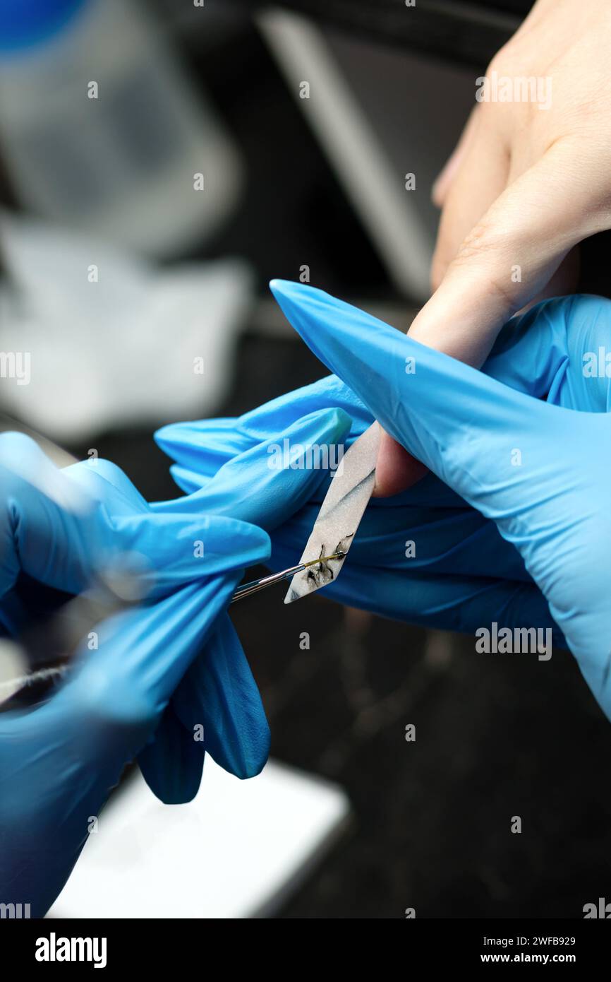 A close-up view of a professional nail technician shaping acrylic nails ...