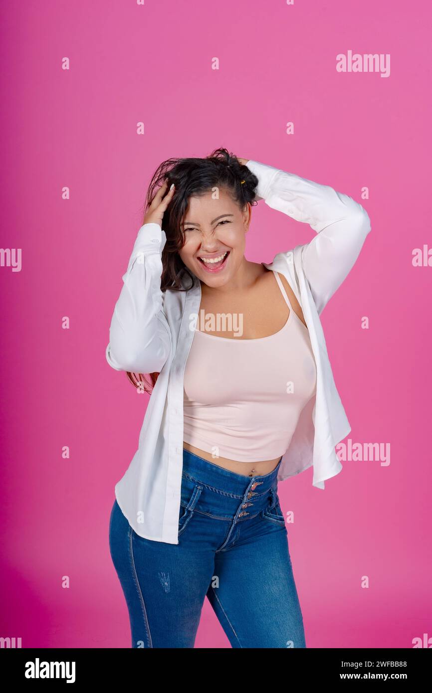 Laughing woman playfully running hands through her hair, casual style ...