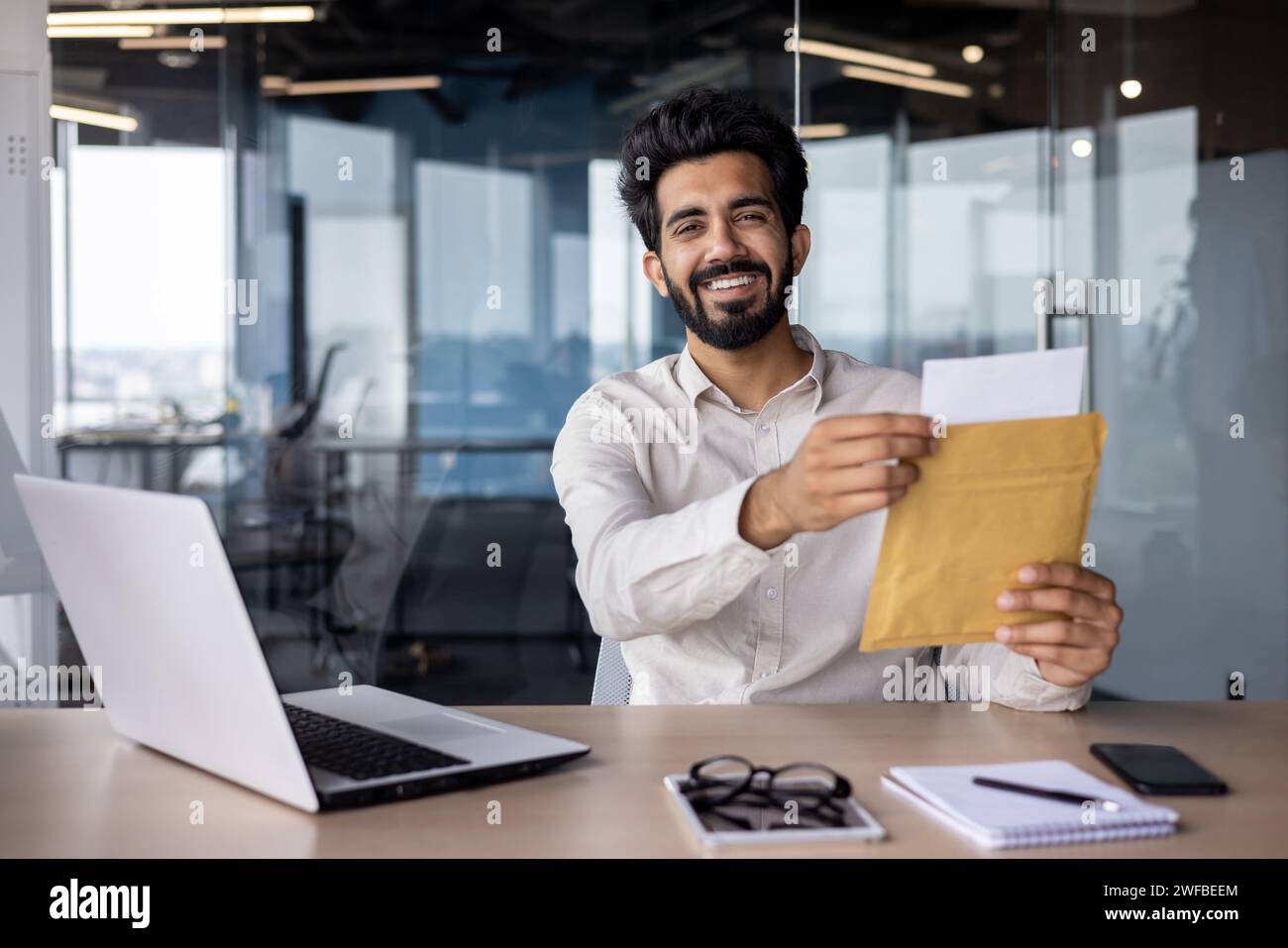 Portrait of a happy young Indian man working in the office, sitting at ...