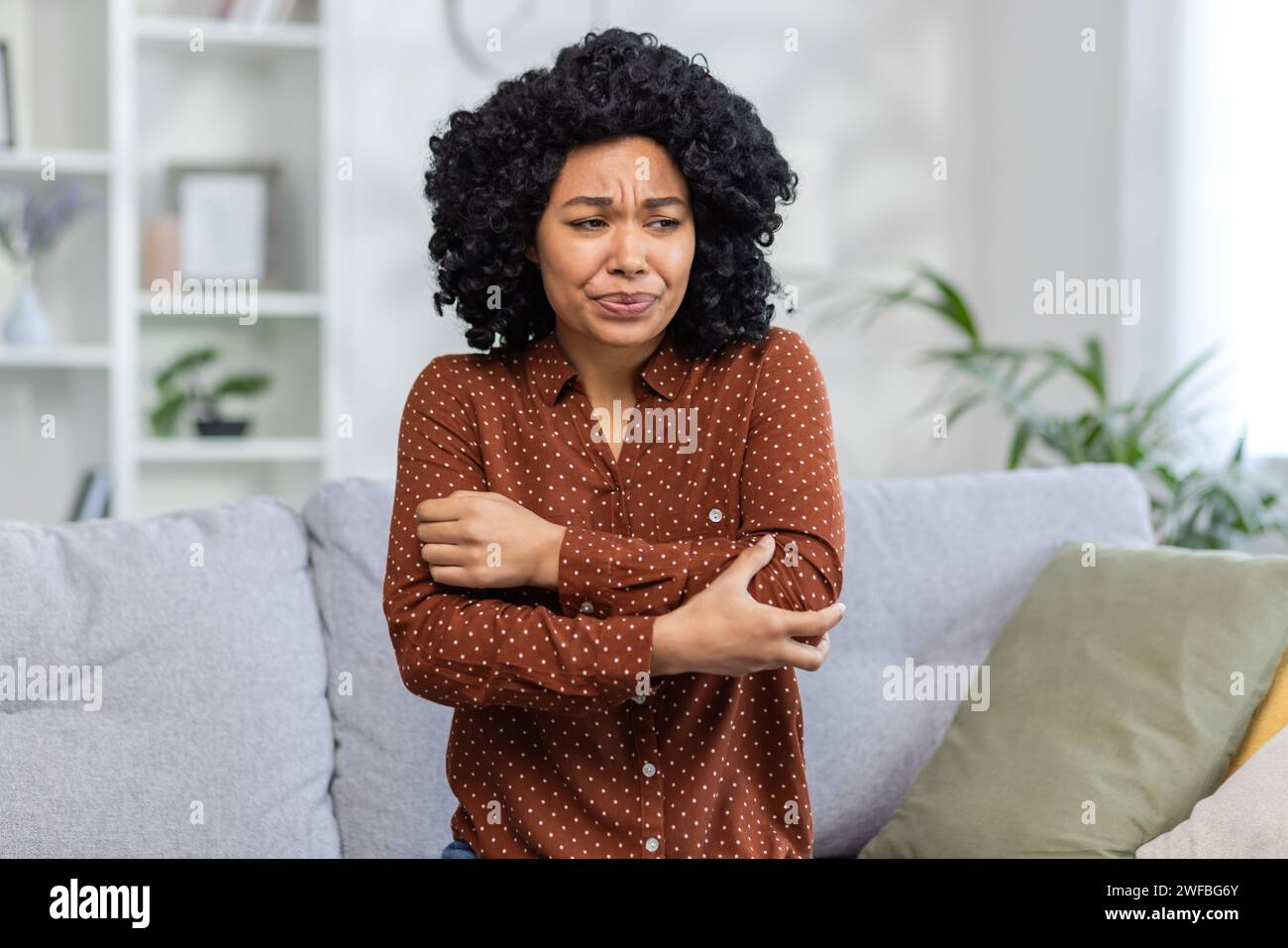 Close-up photo of a sad African-American woman sitting on the sofa at ...