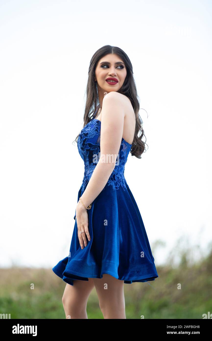 Happy beautiful woman wearing blue evening dress looking back smiling ...