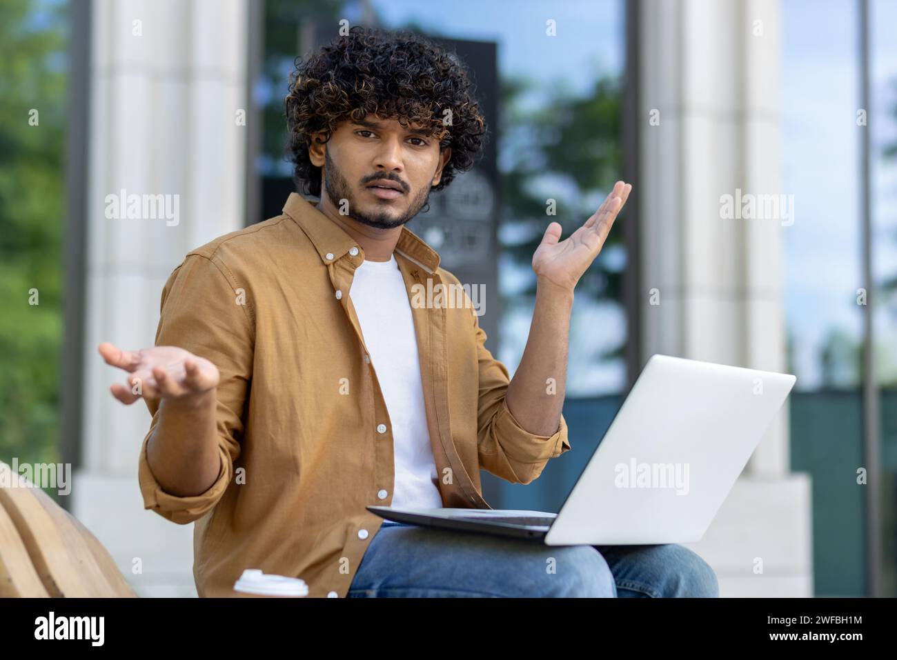 Portrait of a disappointed and worried Indian man sitting with a laptop ...