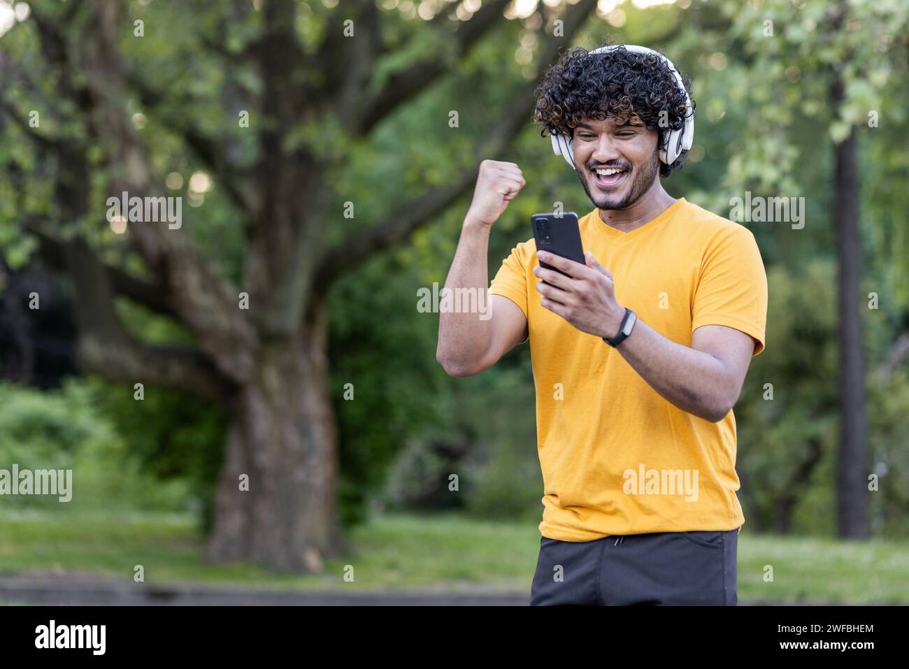 A young Indian sportsman checks his phone and celebrates while ...