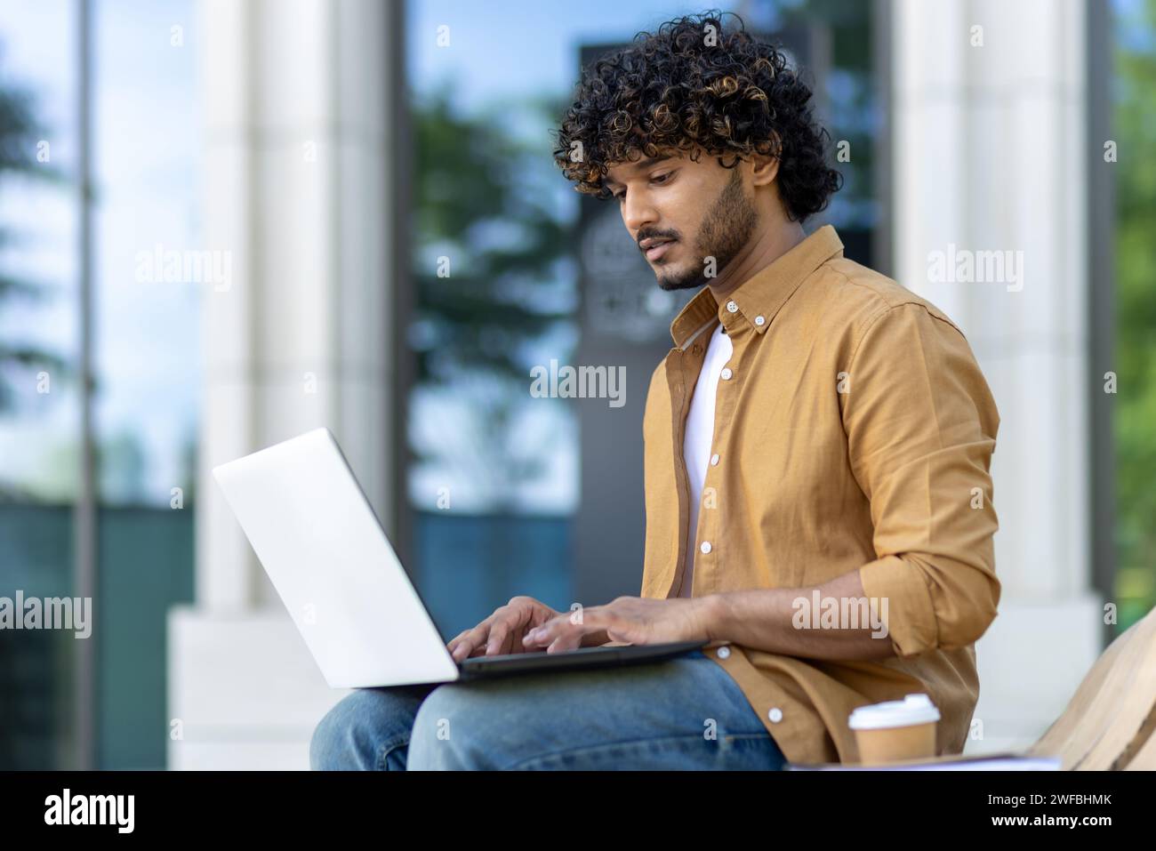 Concentrated and serious young Indian man using a laptop while sitting ...