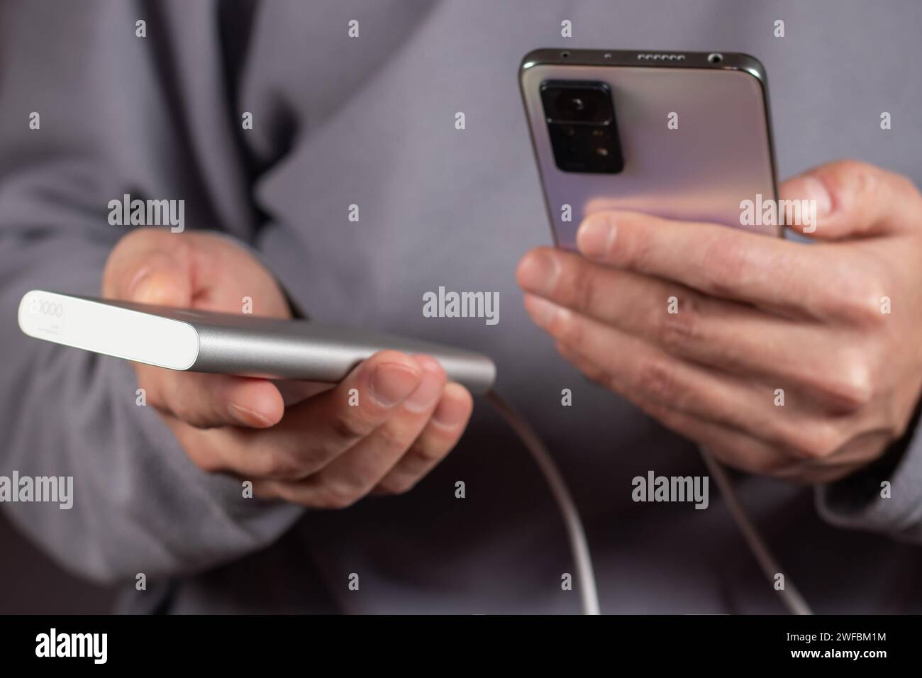 The men hand hold the phone and charger, powerbank and smart phone is ...