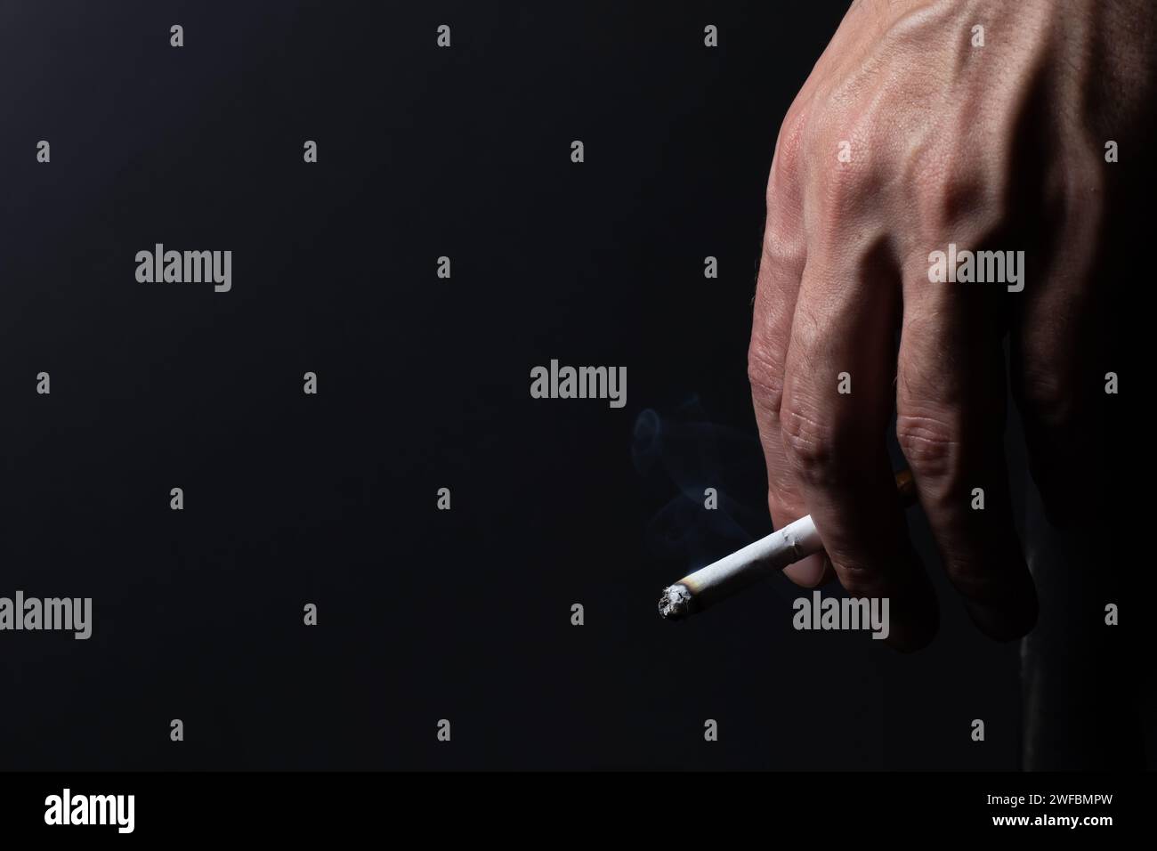 Hand with burning cigarette and smoke on black background Stock Photo ...