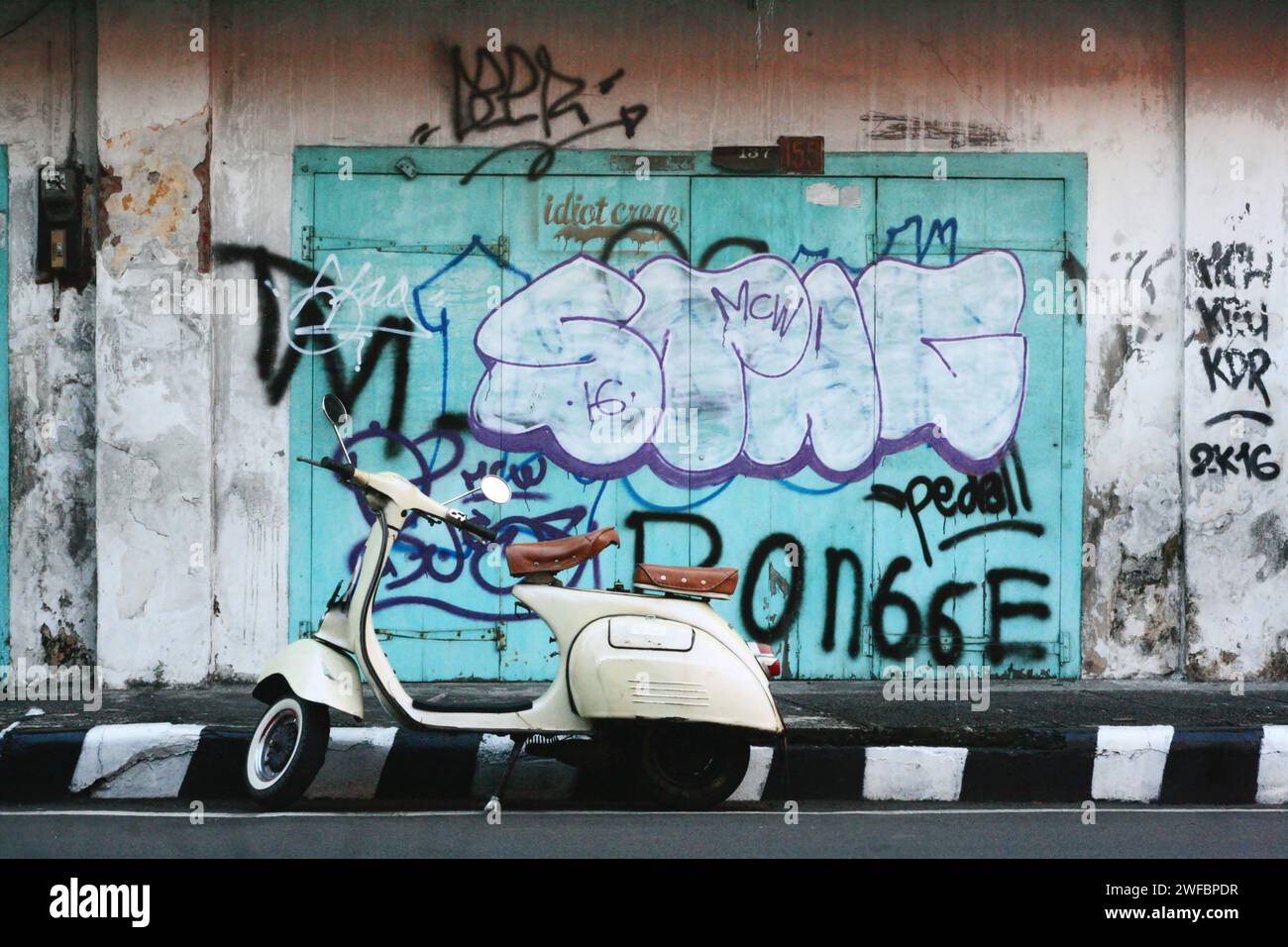 side view of classic scooter vespa parked in side of road with wall ...