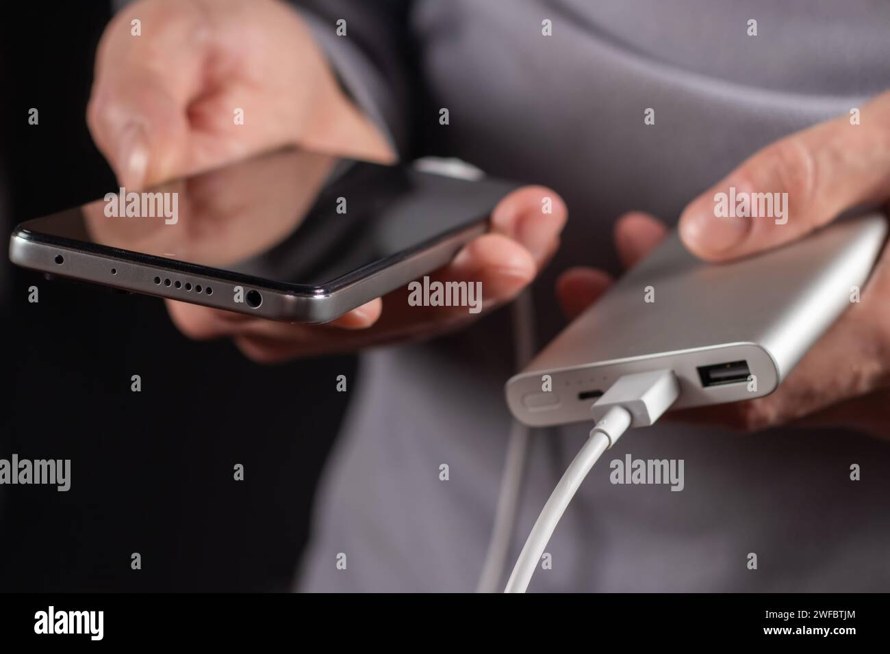 The men hand hold the phone and charger, powerbank and smart phone is ...