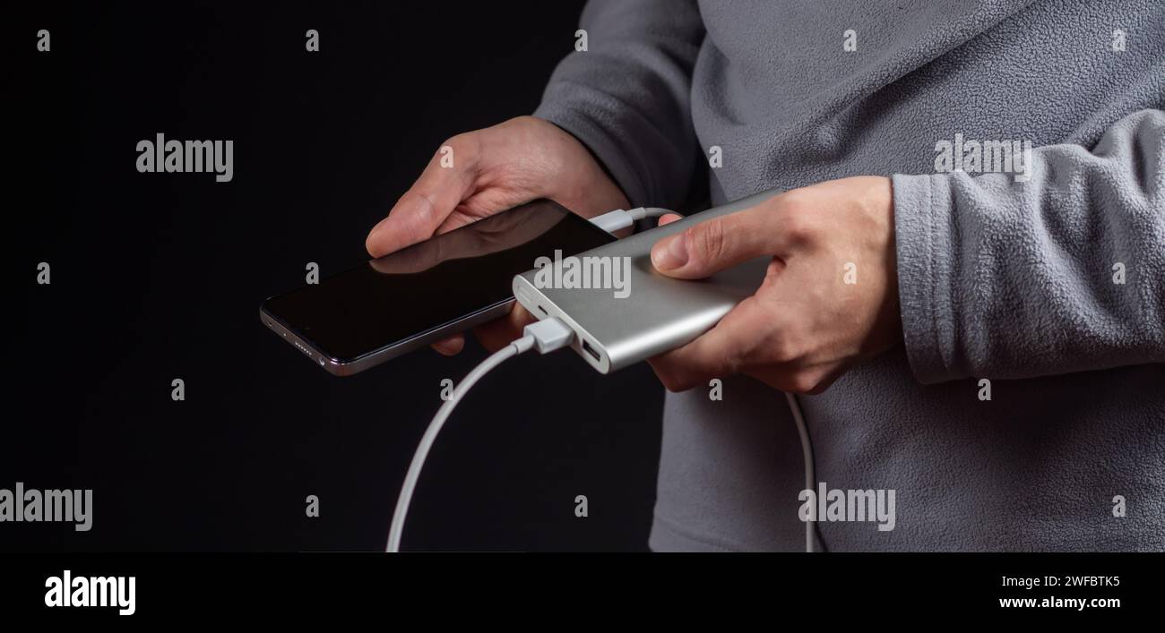 The men hand hold the phone and charger, powerbank and smart phone is ...