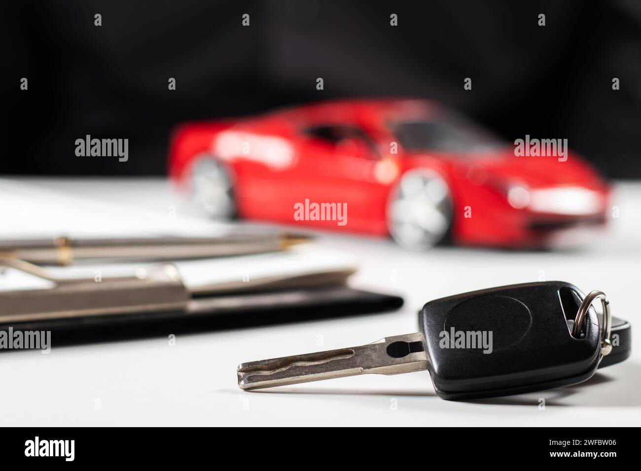 Car insurance form, pen and key on wooden table, and red car background ...