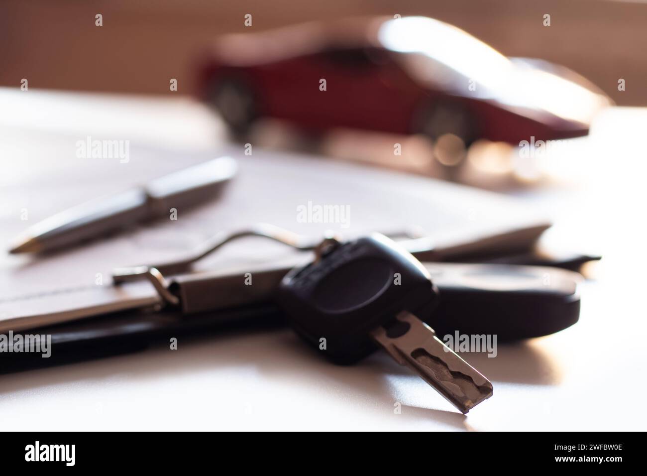 Car keys on purchase documents against the background of a red car ...