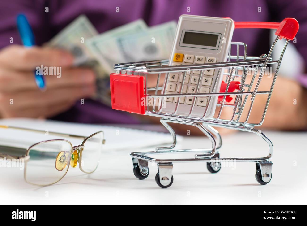 Man calculates the budget. Shopping cart a on table with calculator and ...