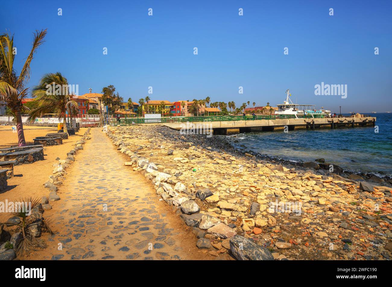 Rocky pathway leading to a colorful pier at Goree Island, Senegal, West ...