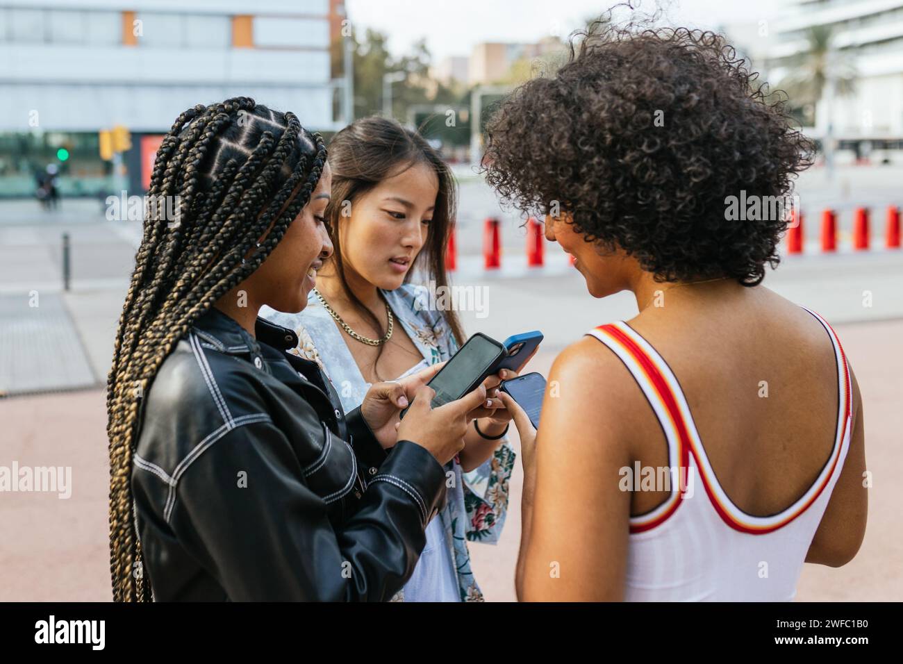 Women and transgender friend using phone in the street Stock Photo - Alamy