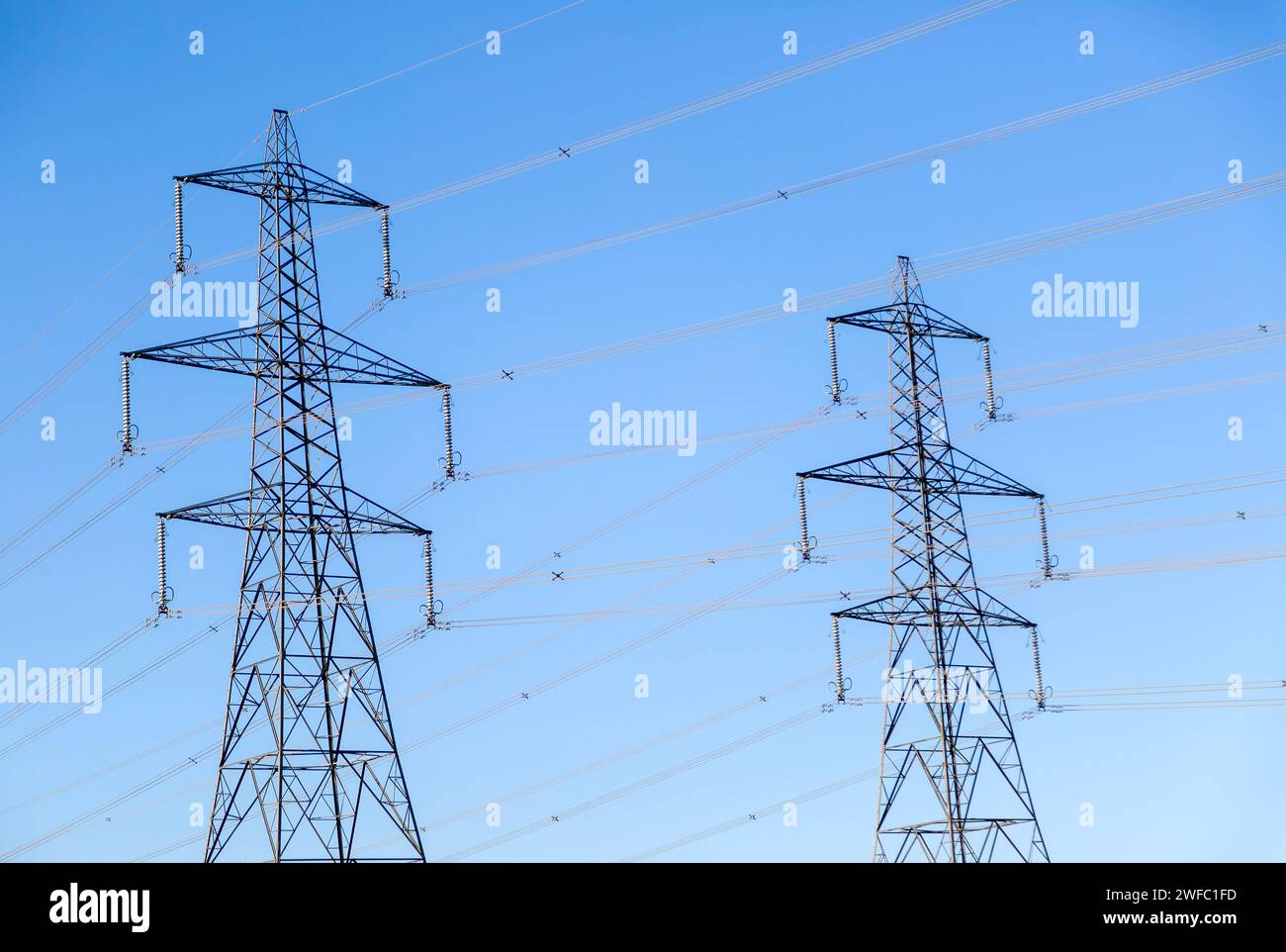 High voltage electricity pylons against blue sky, Suffolk, England, UK ...