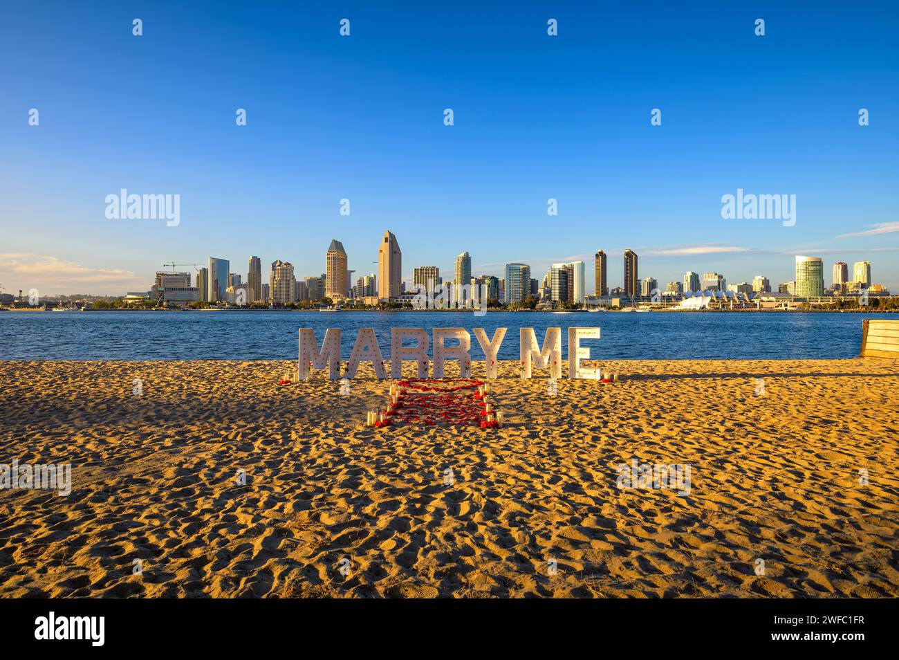 Beach proposal setup with 'Marry Me' sign and skyline of San Diego ...