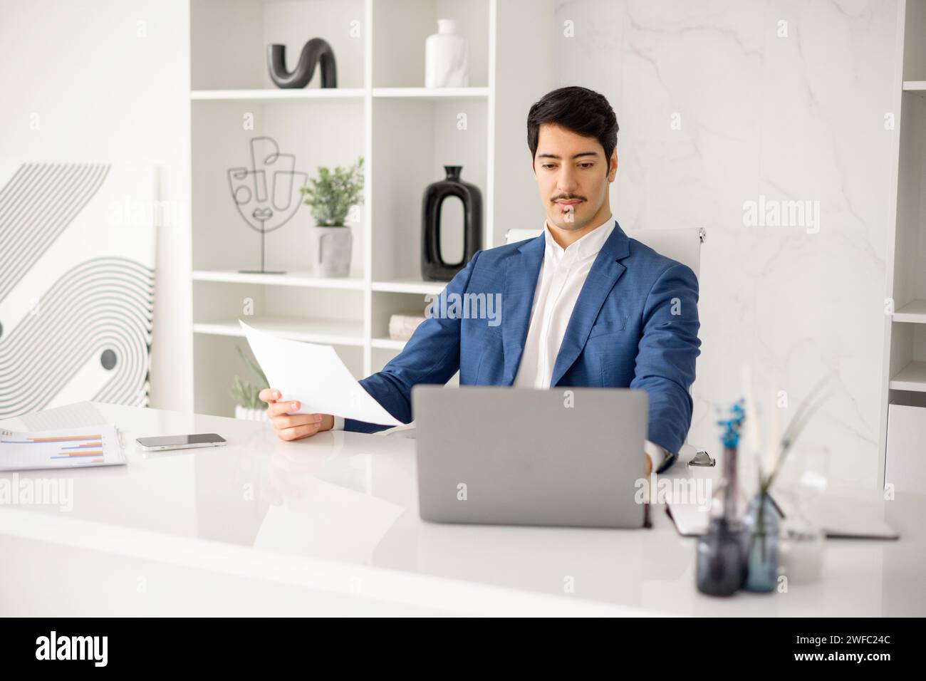 An industrious Hispanic businessman is engrossed in reviewing a paper ...