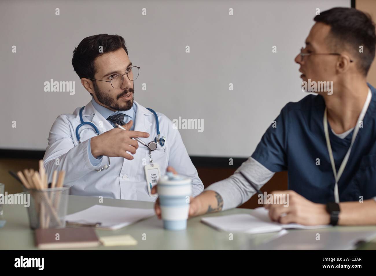 Male Physician Speaking to Coworker at Meeting Stock Photo - Alamy