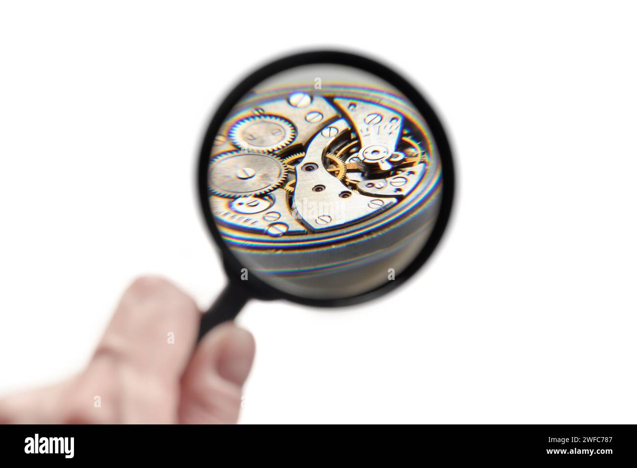 A man examines the mechanism of a old watch through a magnifying glass ...