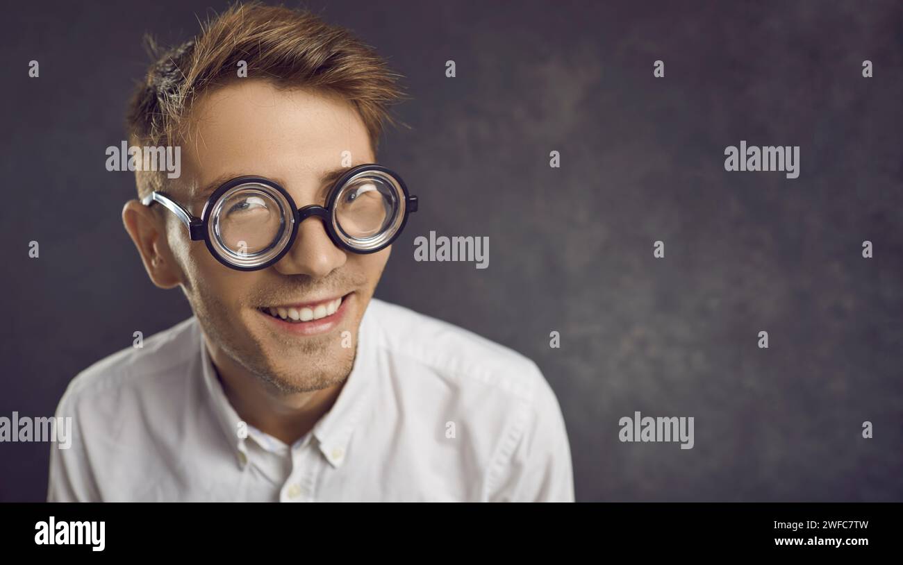 Close up portrait of funny smiling nerd in round glasses on copy space ...