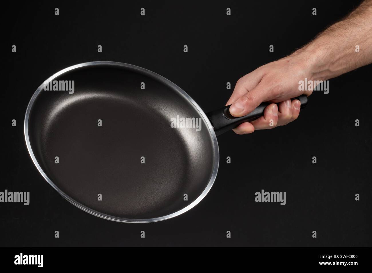 hand holding Frying pan on dark background Stock Photo - Alamy